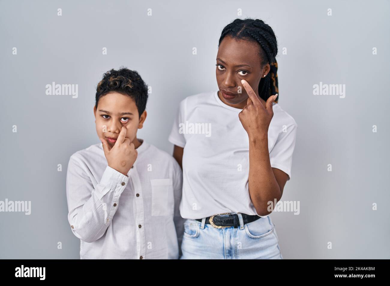 Young mother and son standing together over white background pointing ...