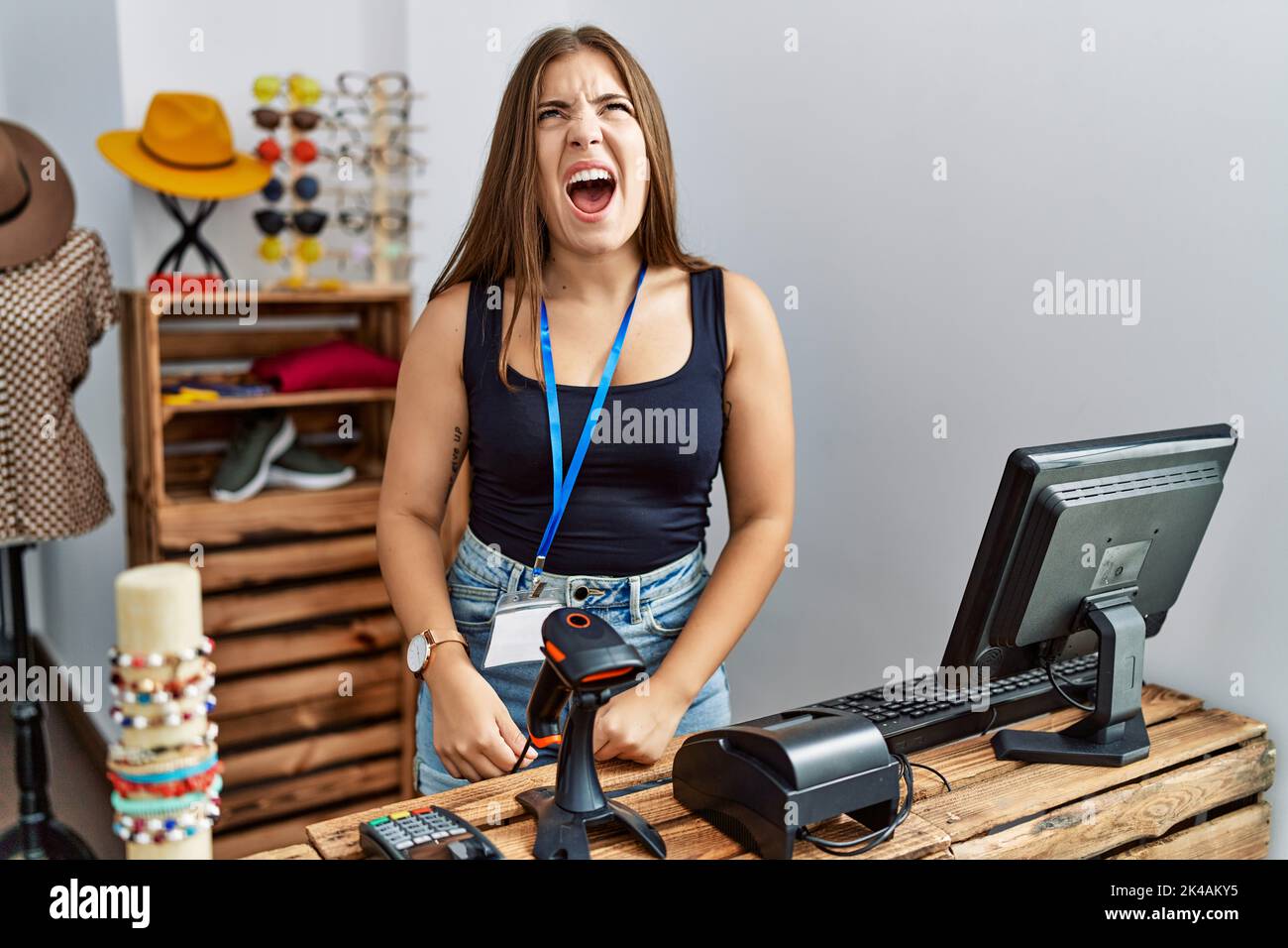 Young brunette woman holding banner with open text at retail shop angry ...