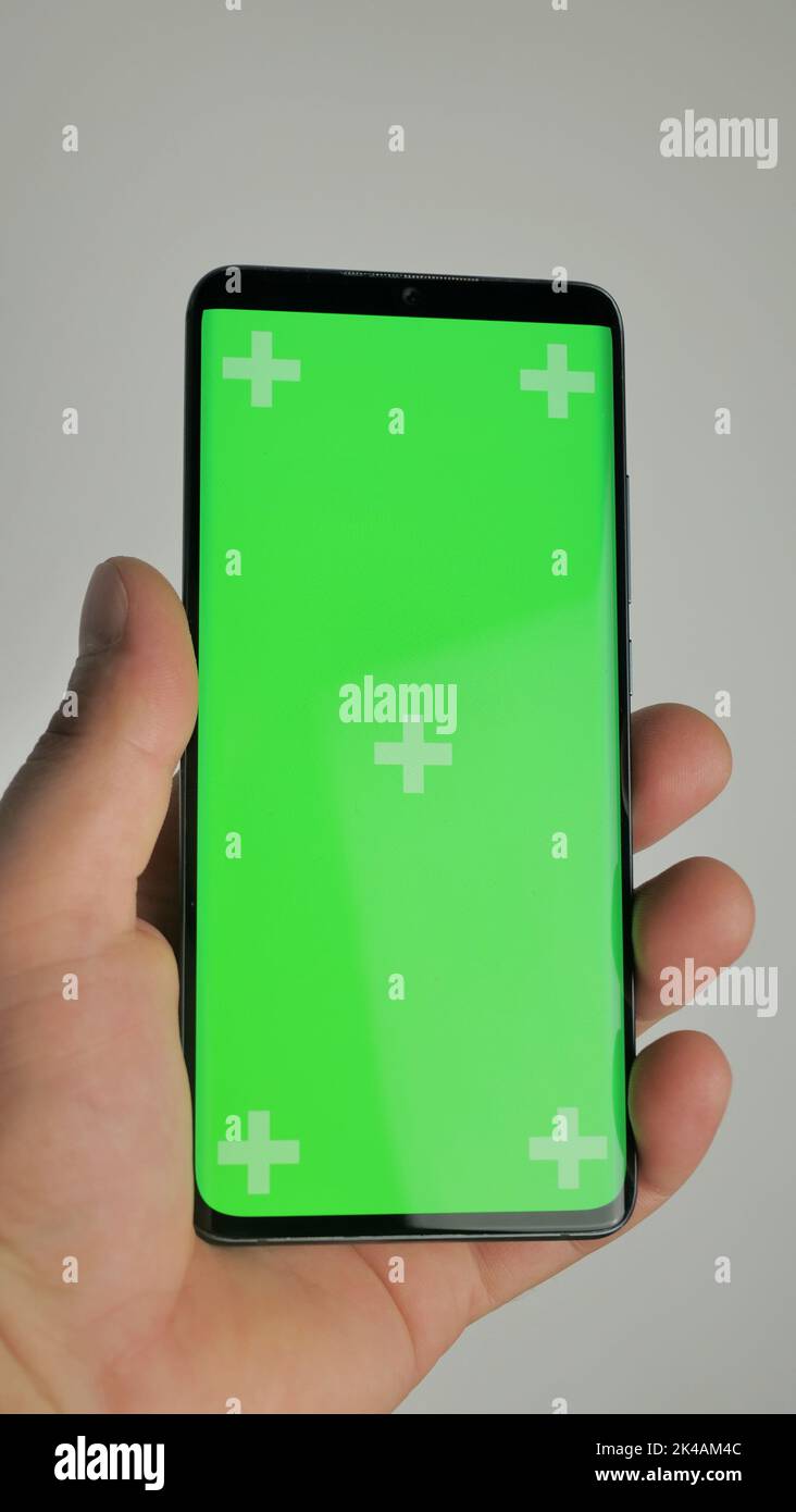 Hand holding smartphone isolated on green background Stock Photo - Alamy