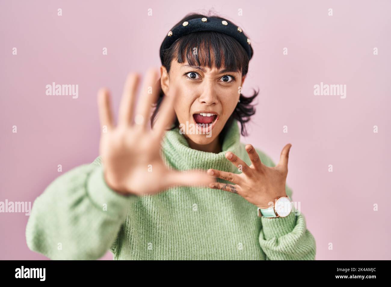 Young beautiful woman standing over pink background afraid and ...