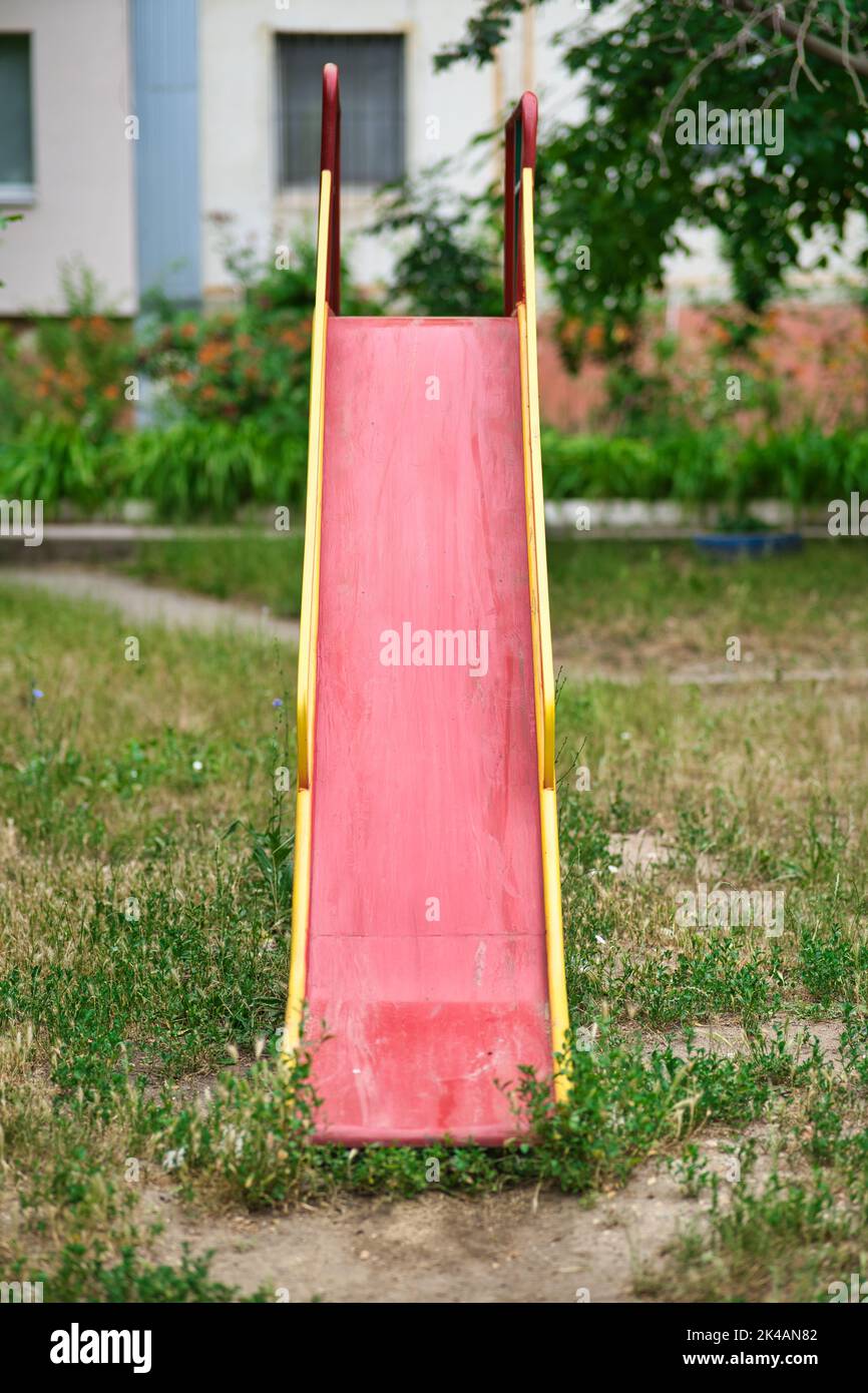 A vertical shot of an old soviet era red metal slide on a playground ...