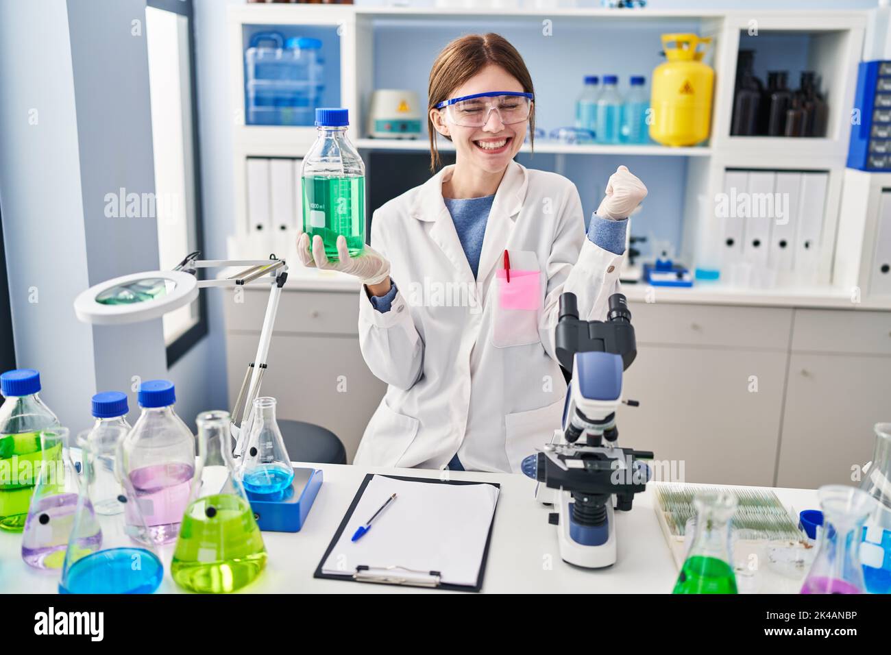 Young brunette woman working at scientist laboratory screaming proud ...