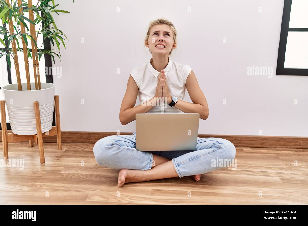 Young blonde woman using computer laptop sitting on the floor at the ...