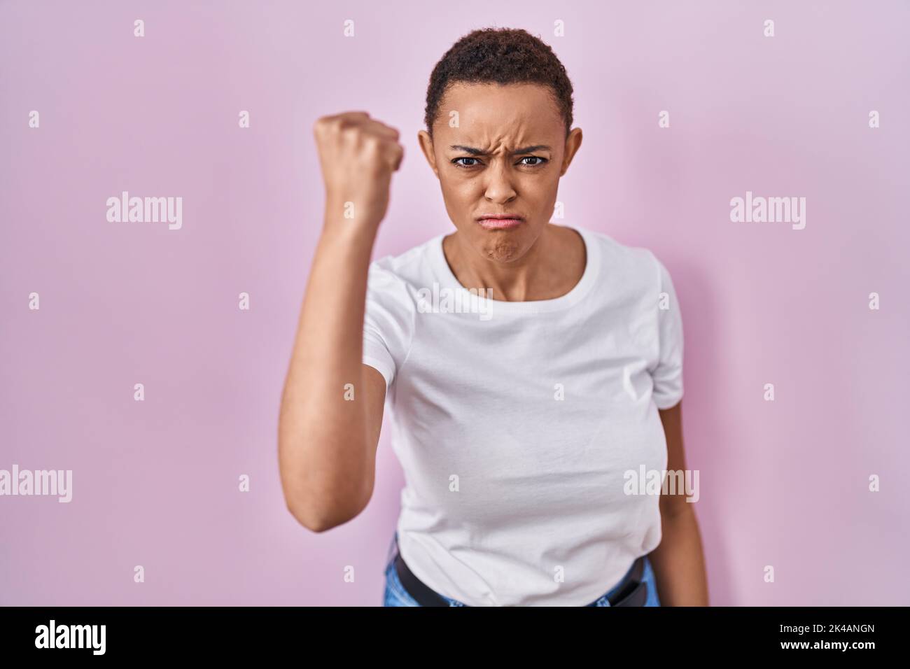Beautiful african american woman standing over pink background angry ...