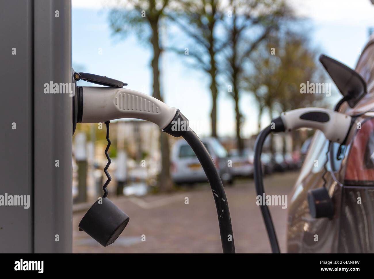 Charging of modern electric car on the street, focus on the plugged ...