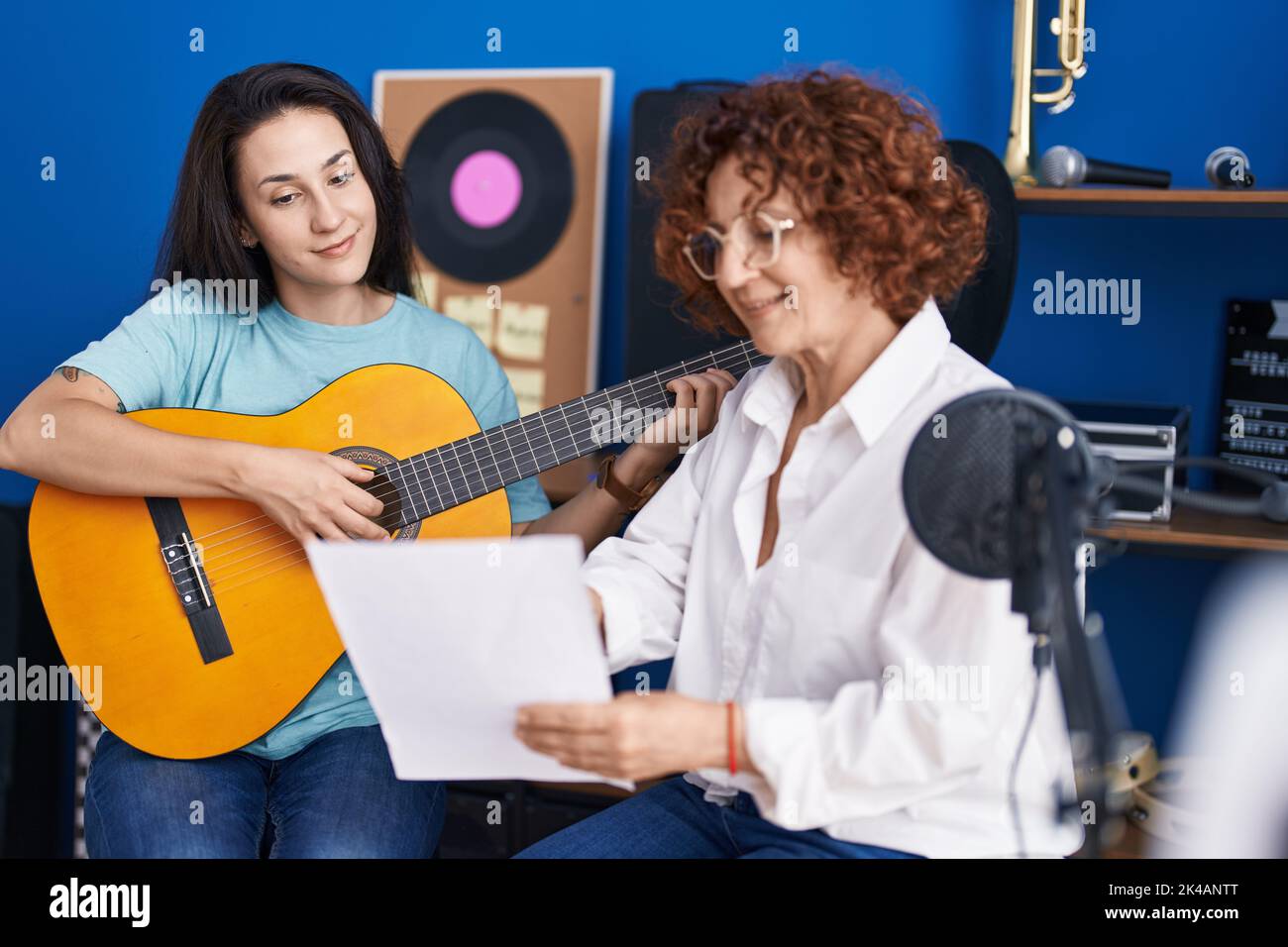 Two women musicians having classical guitar lesson at music studio ...