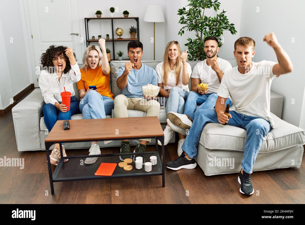 Group of people eating snack sitting on the sofa at home annoyed and ...