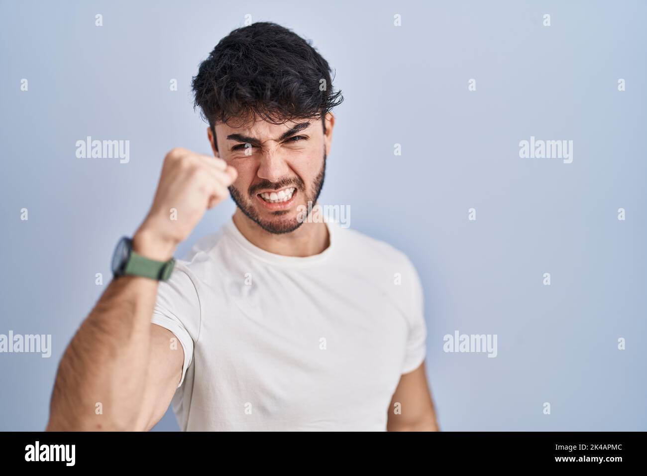 Hispanic man with beard standing over white background angry and mad ...