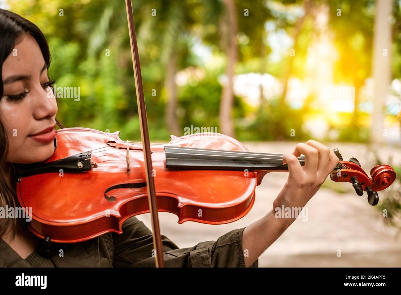 Close up of a girl with her violin playing a melody outdoors, Concept ...