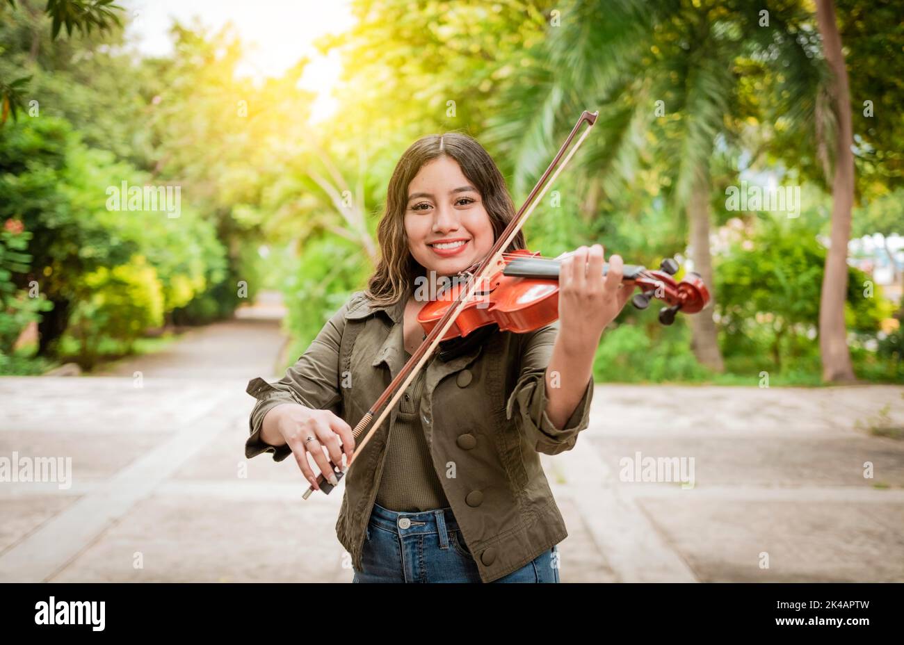 Young woman playing the violin outdoors. Portrait of a girl playing the ...
