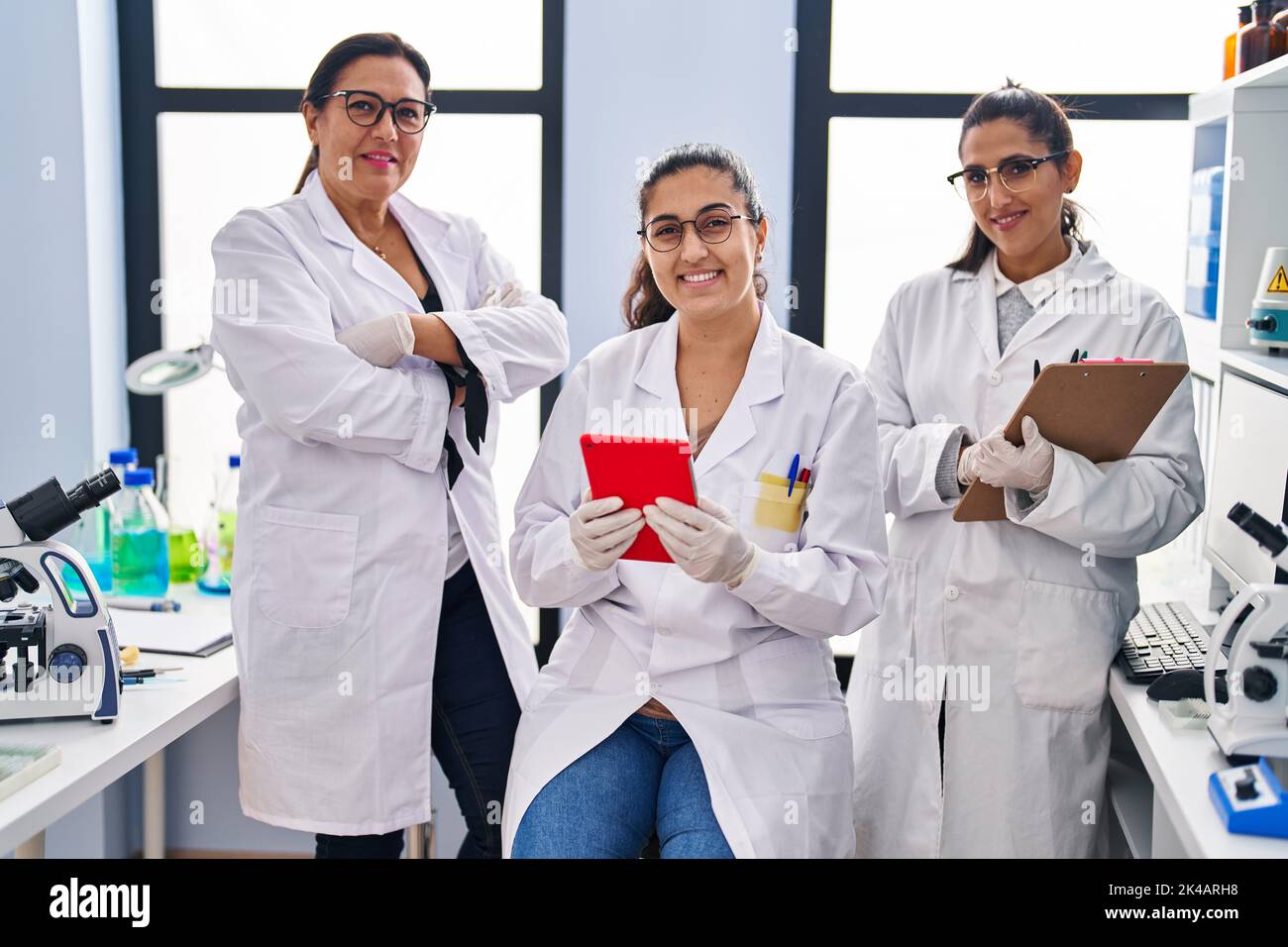 Three woman scientists using touchpad write on checklist at laboratory ...