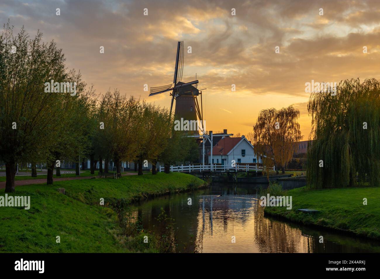 Typical dutch scenery with a canal and a windmill by the sunset, in ...