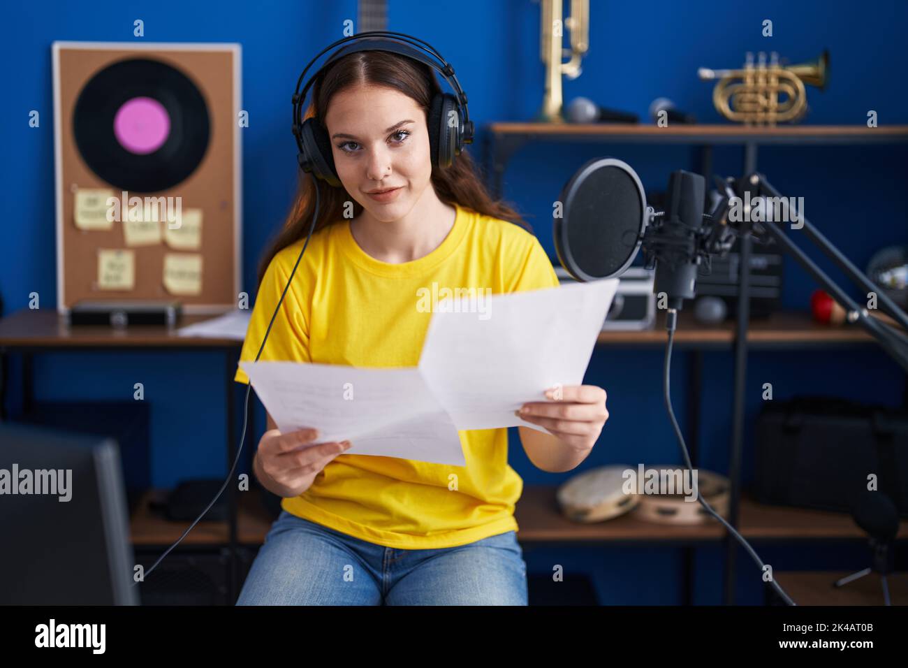 Young woman musician listening to music reading song at music studio ...