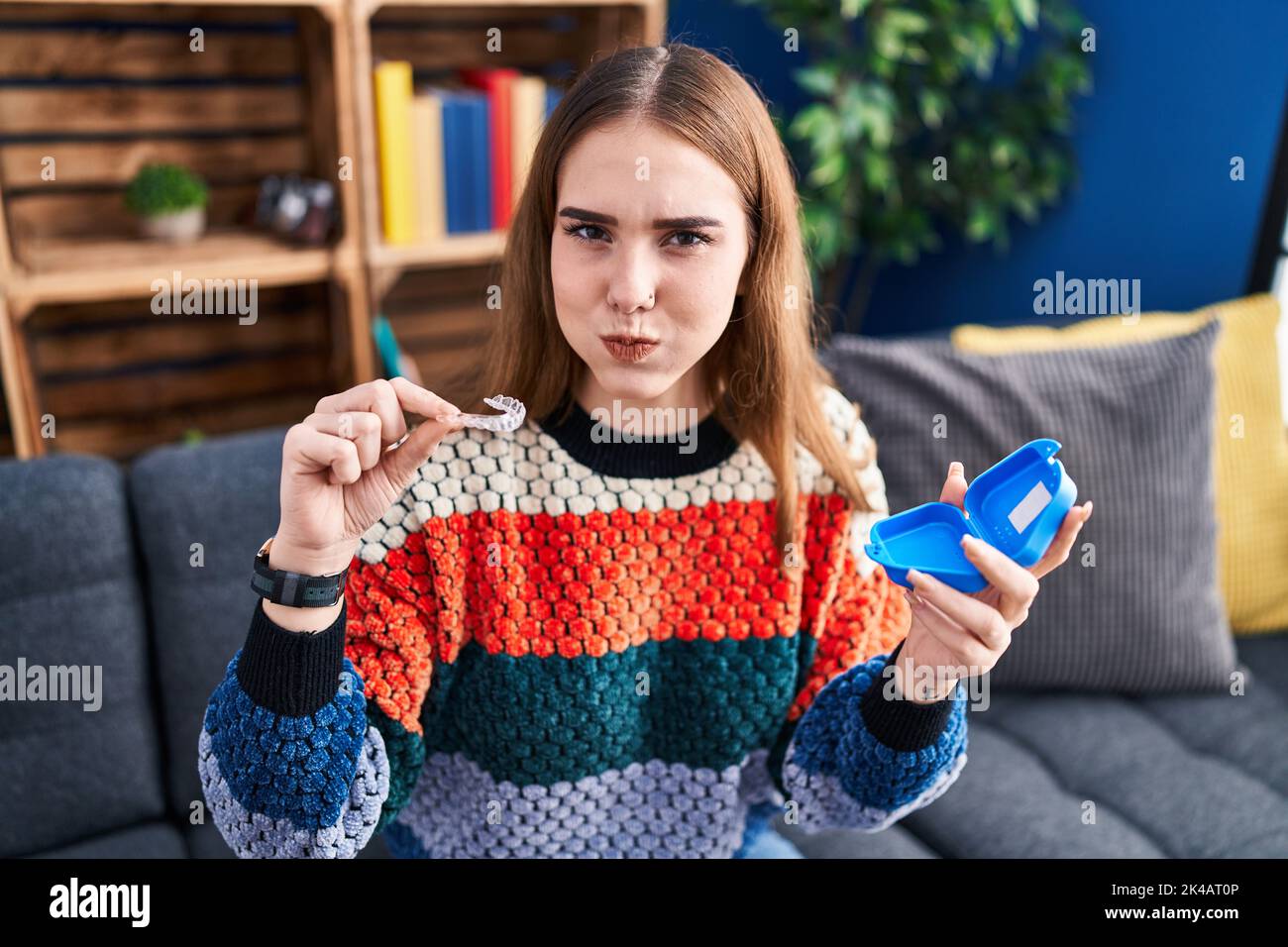 Young hispanic girl holding invisible aligner orthodontic puffing ...