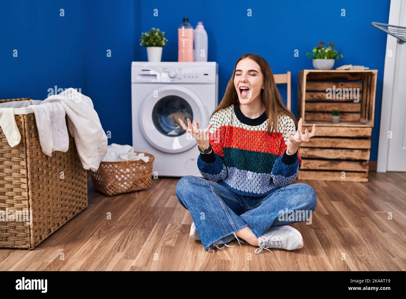 Young hispanic girl doing laundry celebrating mad and crazy for success ...