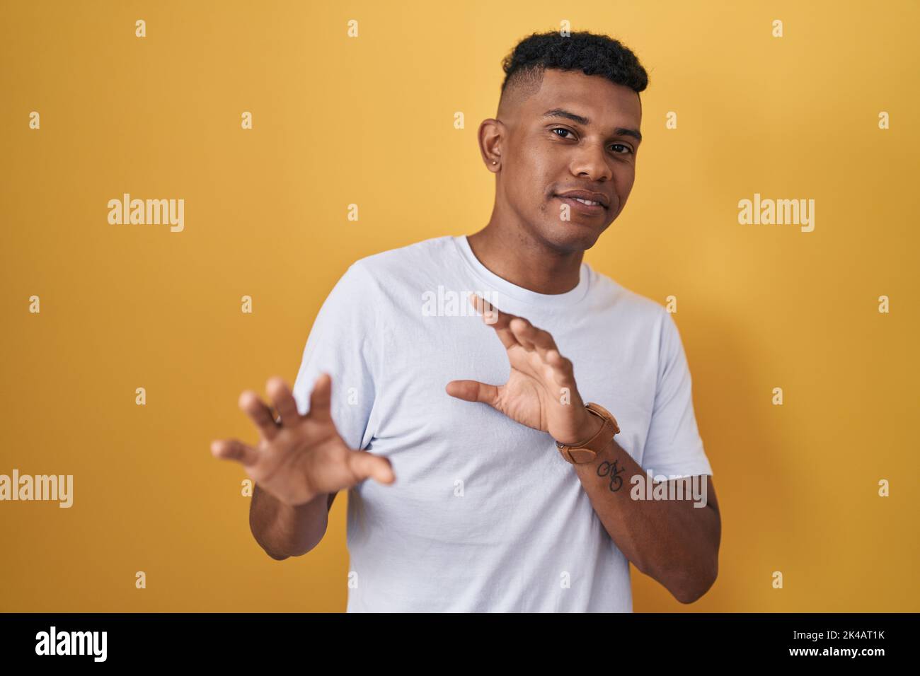 Young hispanic man standing over yellow background disgusted expression ...