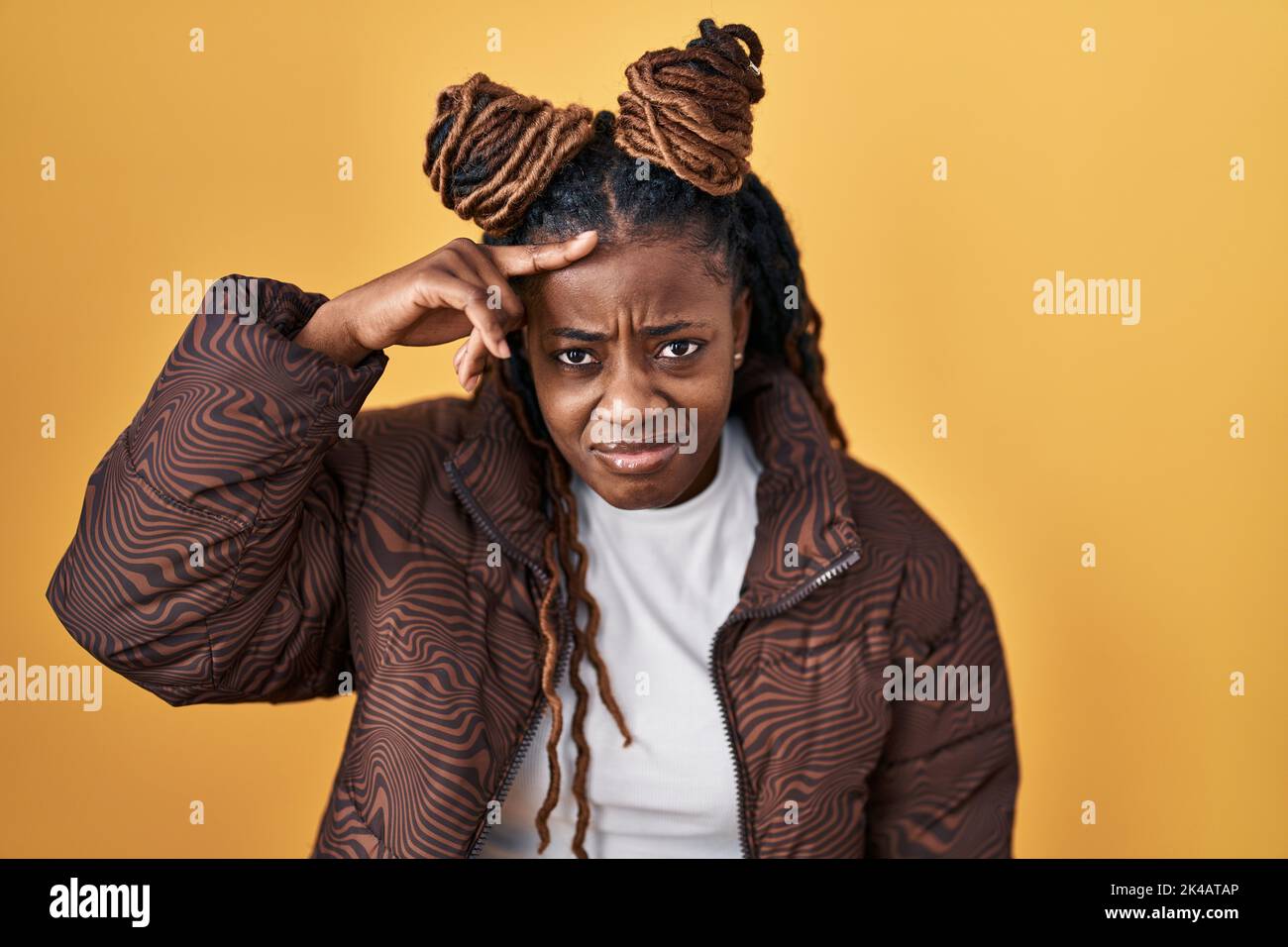 African woman with braided hair standing over yellow background ...