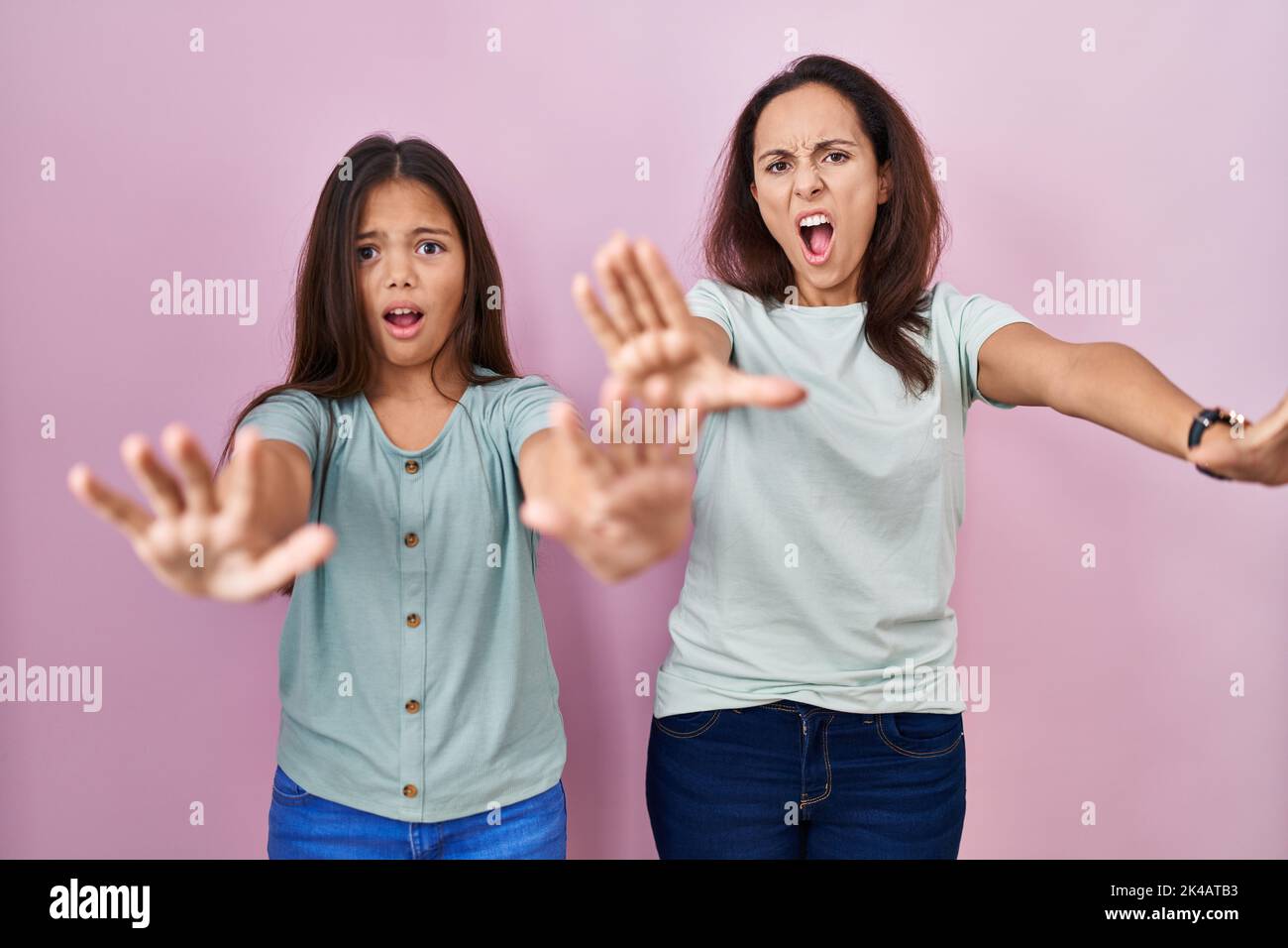 Young Mother And Daughter Standing Over Pink Background Doing Stop