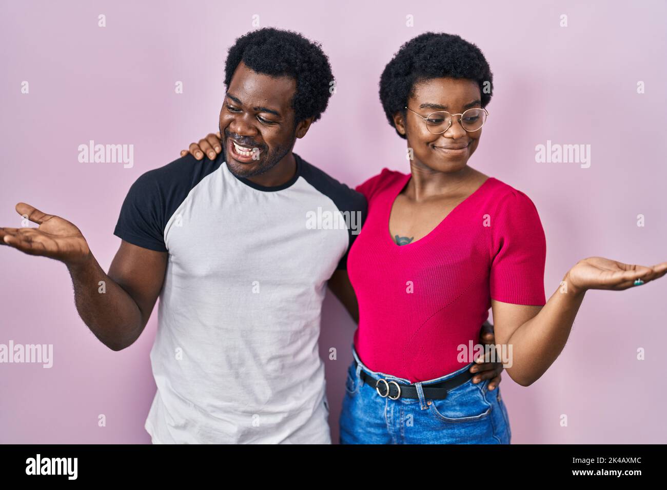 Young african american couple standing over pink background smiling ...