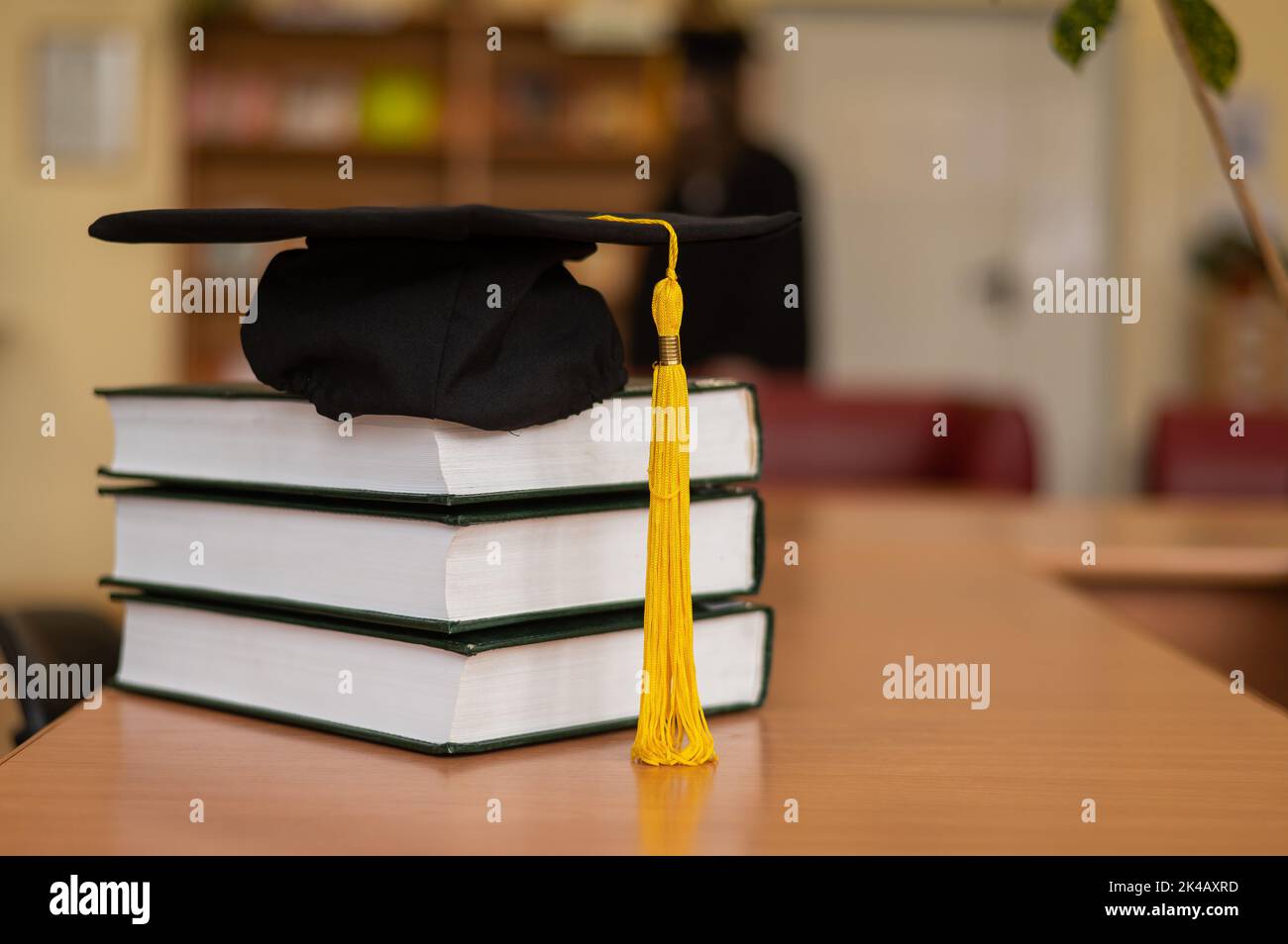 Graduation cap on a stack of books in the library Stock Photo - Alamy