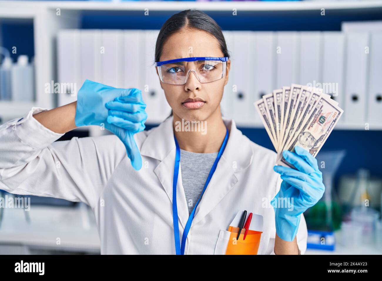 Young brazilian woman working at scientist laboratory holding money ...