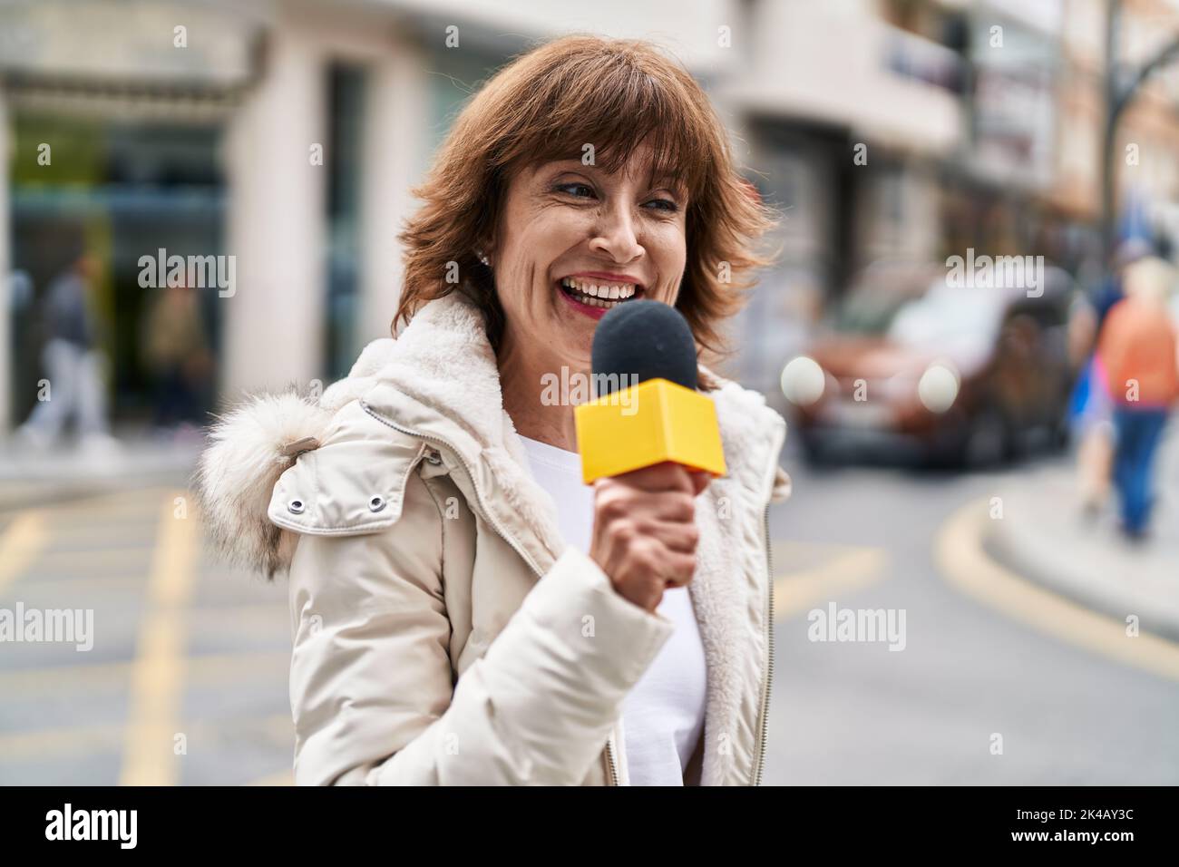 Middle age woman reporter working using microphone at street Stock Photo - Alamy