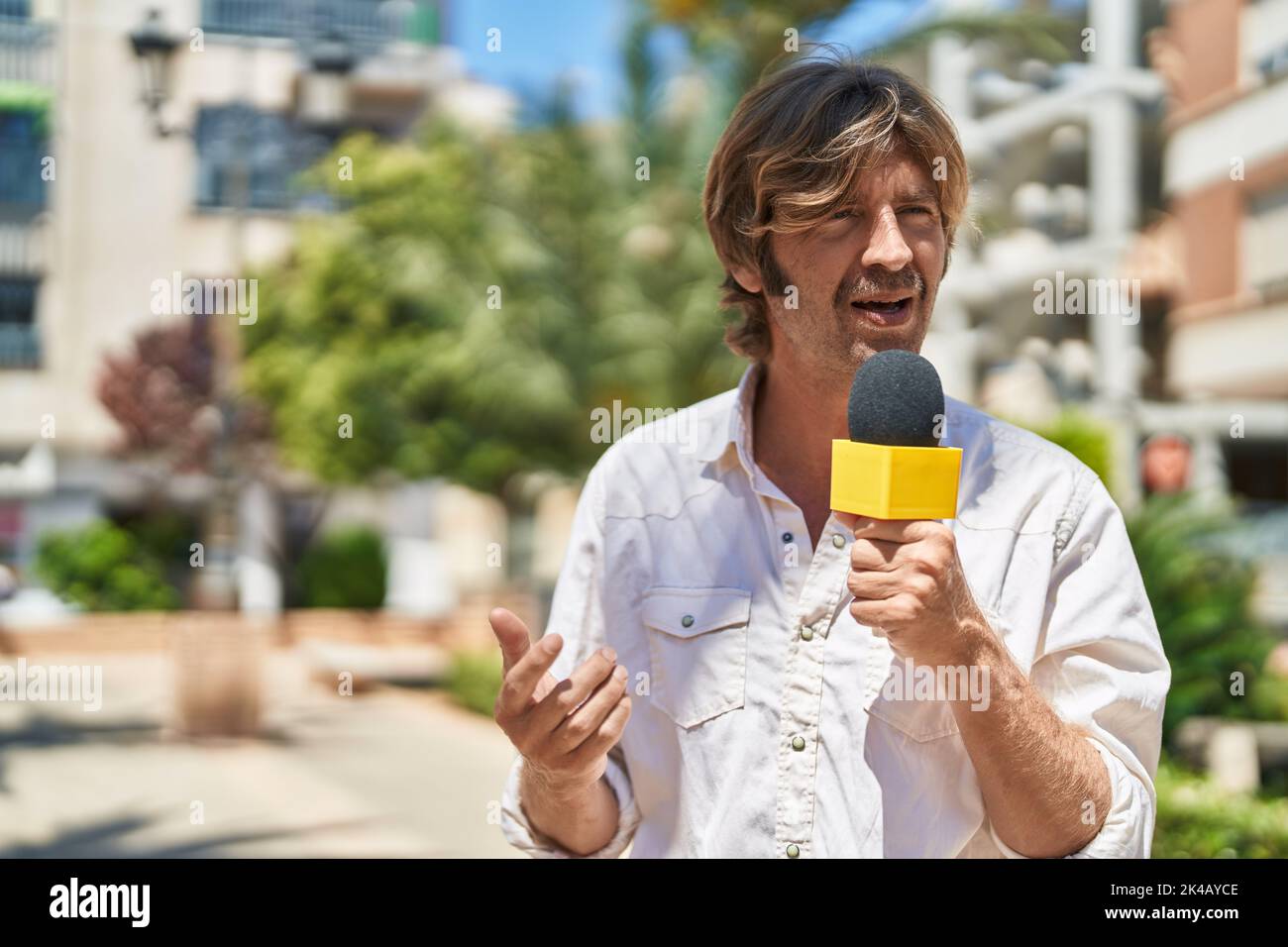 Young man reporter working using microphone at park Stock Photo - Alamy