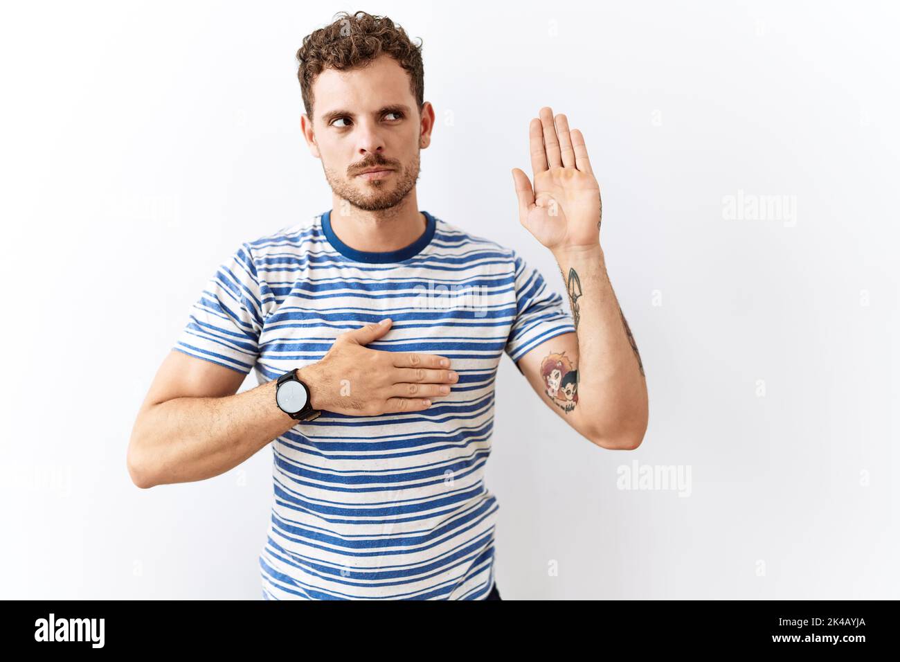 Handsome young man standing over isolated background swearing with hand ...
