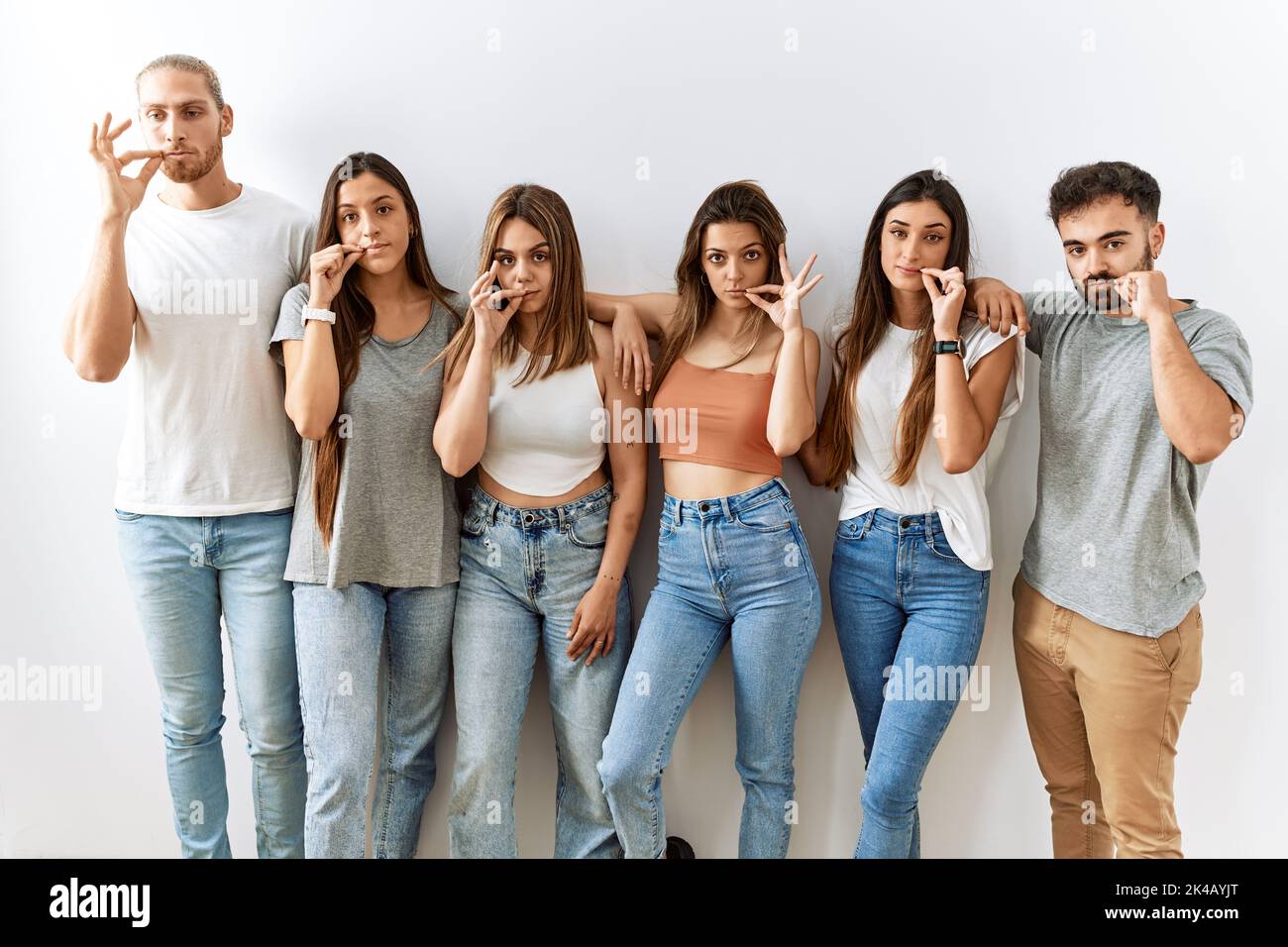Group of young friends standing together over isolated background mouth ...