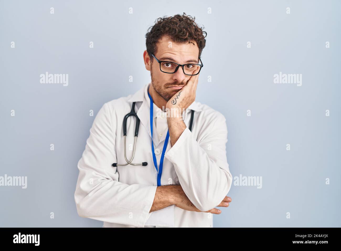 Young hispanic man wearing doctor uniform and stethoscope thinking ...