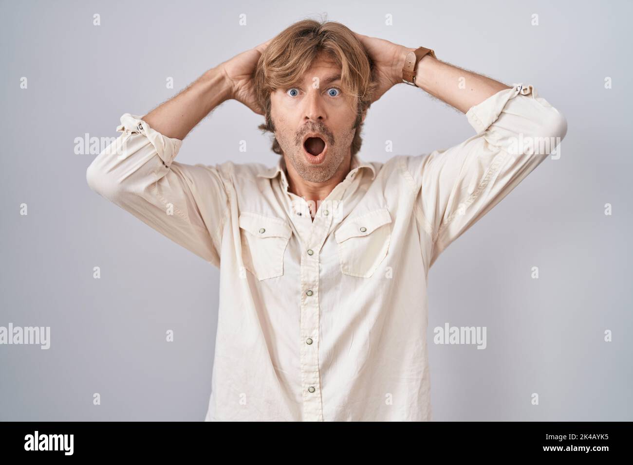 Middle age man standing over isolated background crazy and scared with ...