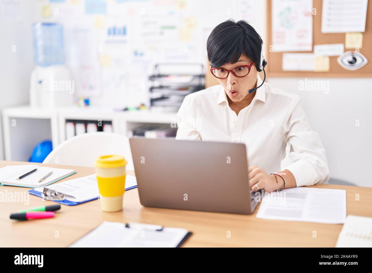 Young asian woman with short hair wearing call center agent headset ...