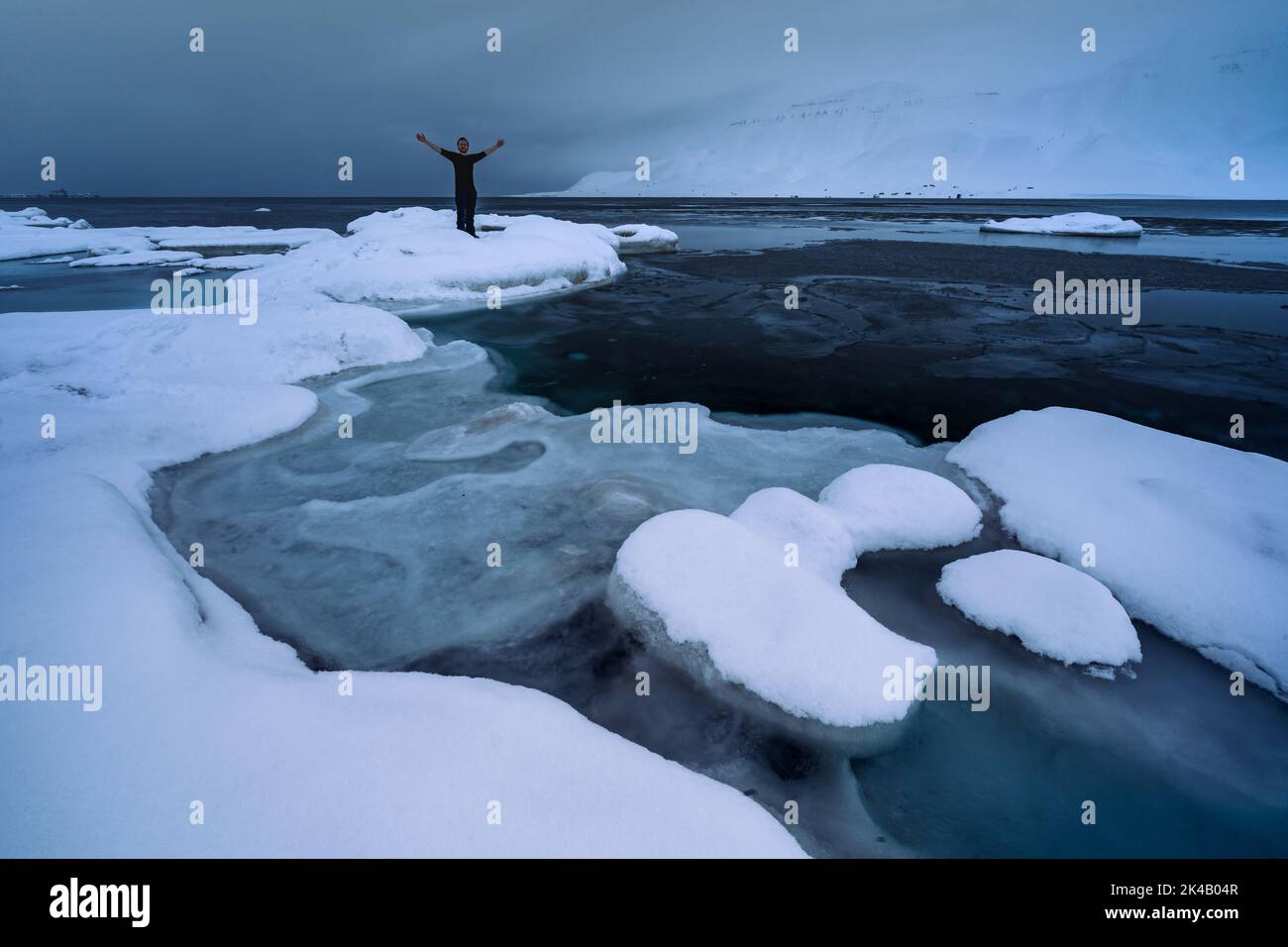 Man standing on frozen ice block on coast of winter Longyearbyen ...