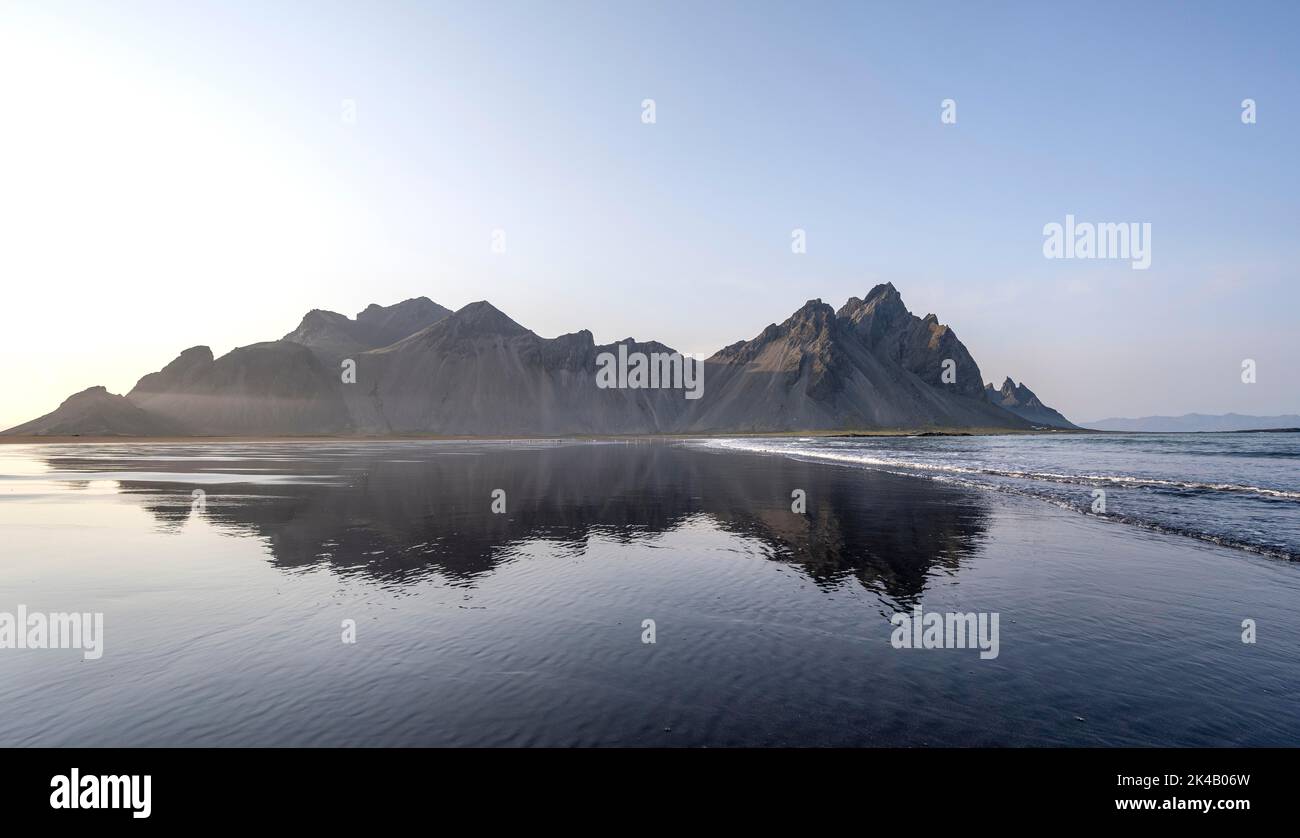 Black lava beach, sandy beach and sea, mountains Klifatindur reflected ...