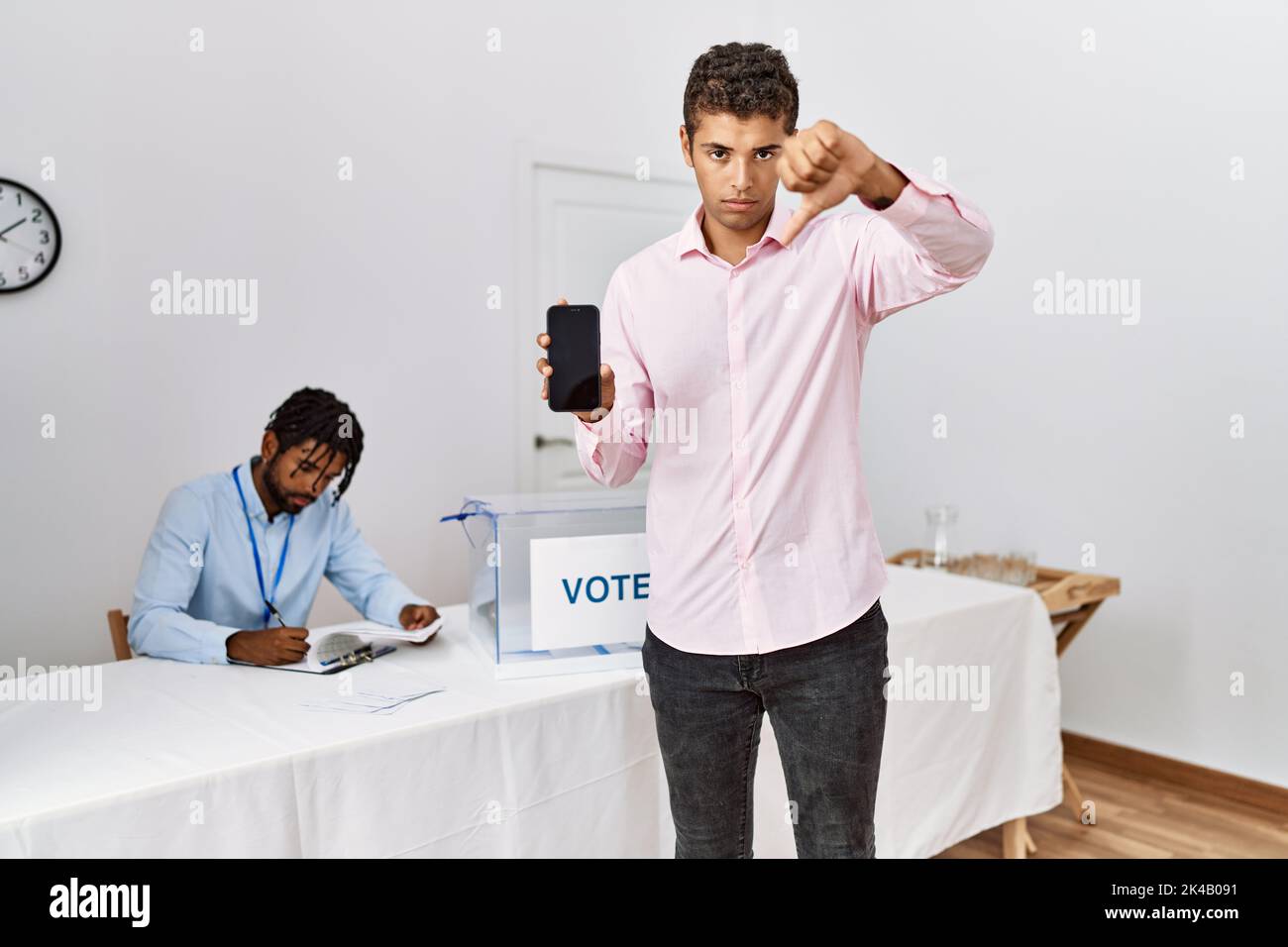 Young hispanic men at political campaign election holding smartphone ...
