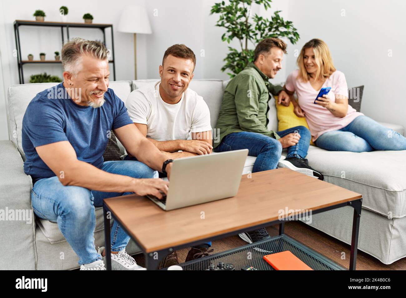 Group of middle age friends smiling happy using smartphone and laptop ...