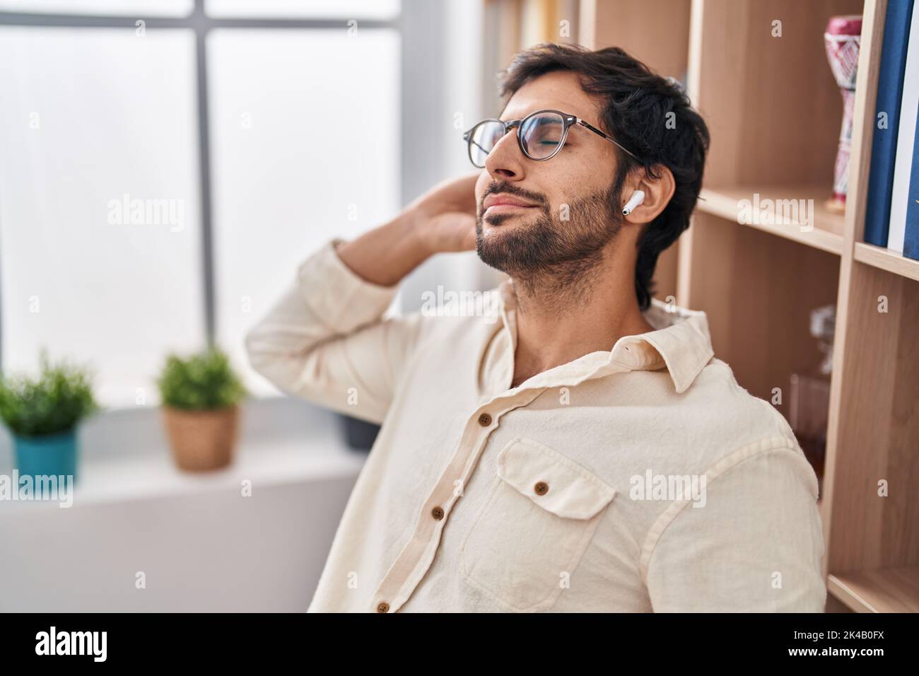 Young hispanic man listening to music sitting on table at home Stock ...