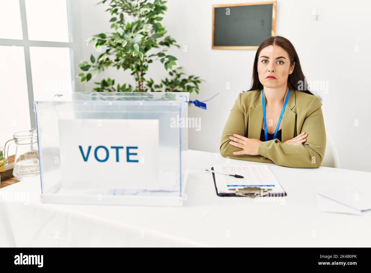 Young brunette woman sitting at election table with voting ballot ...