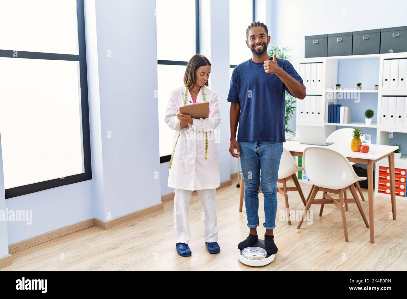 Dietitian at the clinic with client checking weight smiling happy and ...