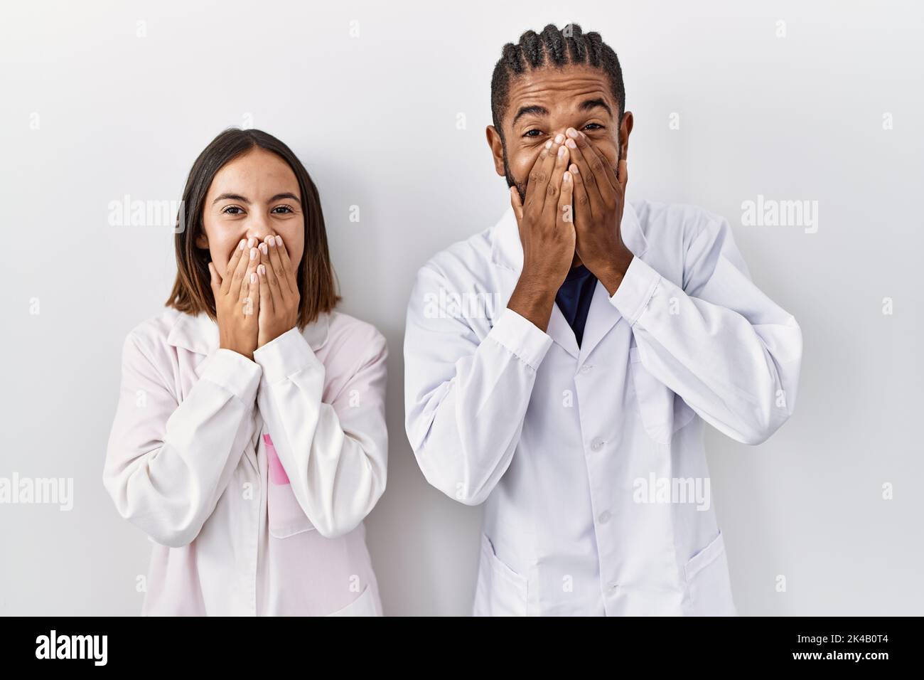 Young hispanic doctors standing over white background laughing and ...