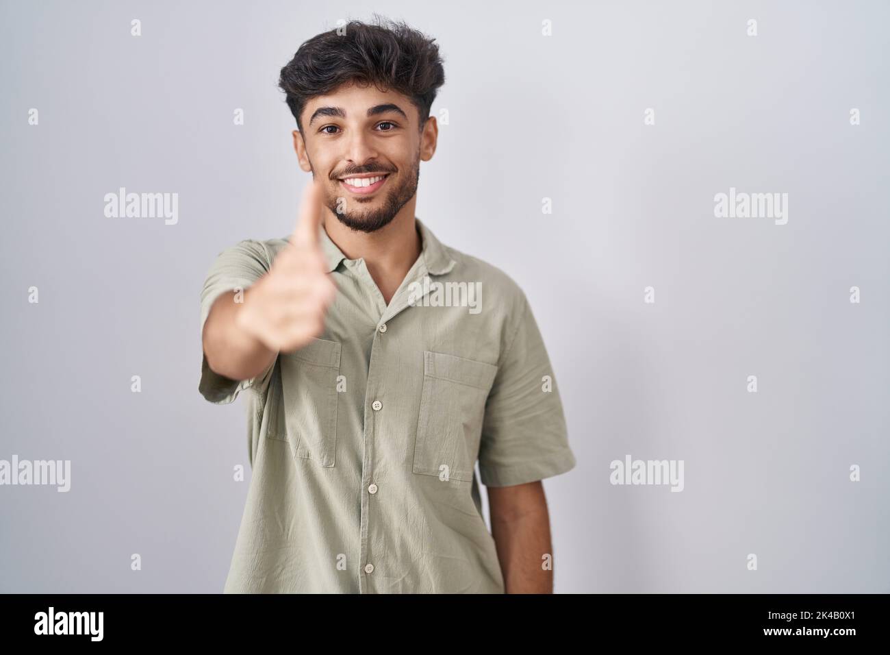 Arab man with beard standing over white background smiling friendly ...