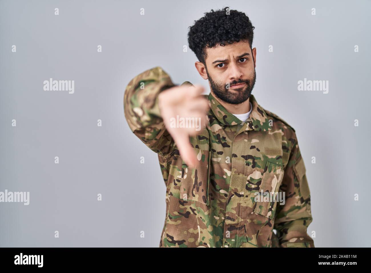Arab man wearing camouflage army uniform looking unhappy and angry ...