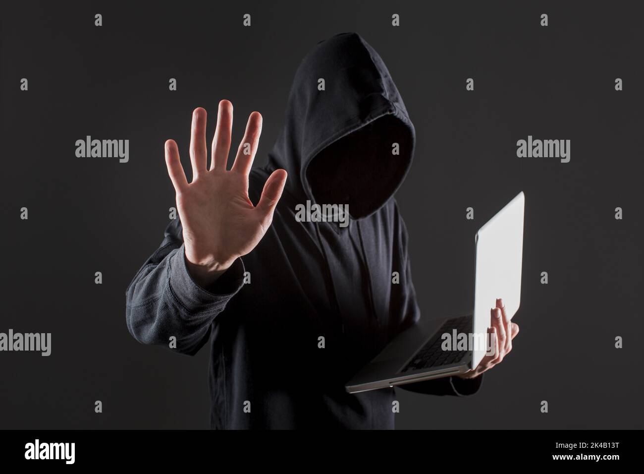 Side view male hacker holding laptop putting hand up as stop ...