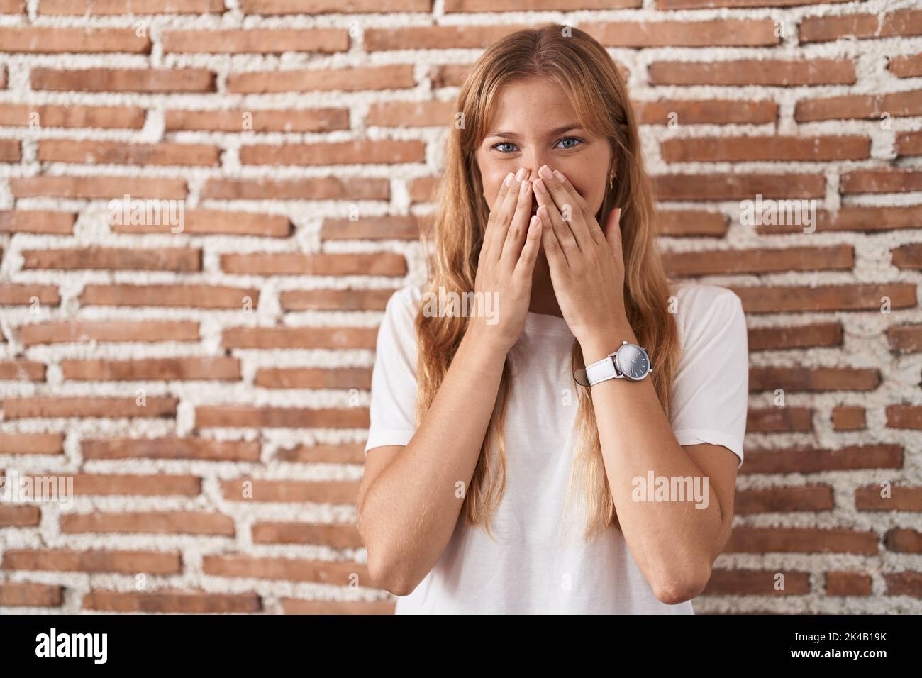 Young caucasian woman standing over bricks wall laughing and ...