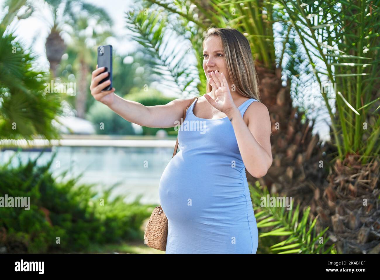 Young pregnant woman doing video call with smartphone looking positive ...