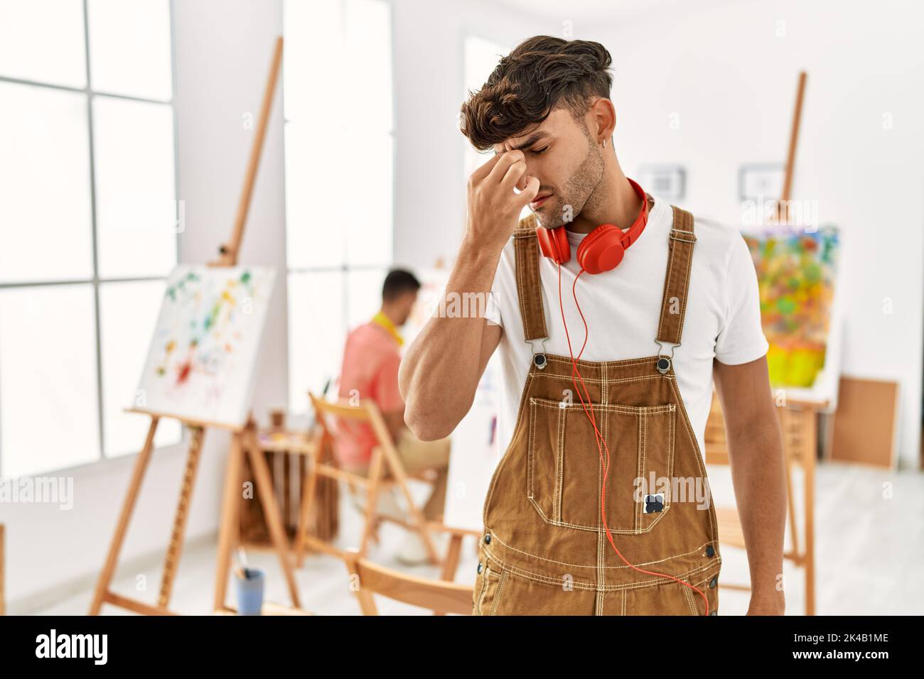 Young hispanic man at art studio tired rubbing nose and eyes feeling ...