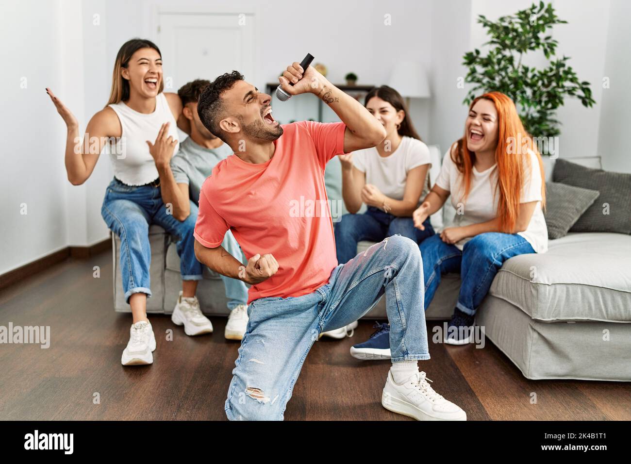 Group of young friends having party singing song using microphone at ...