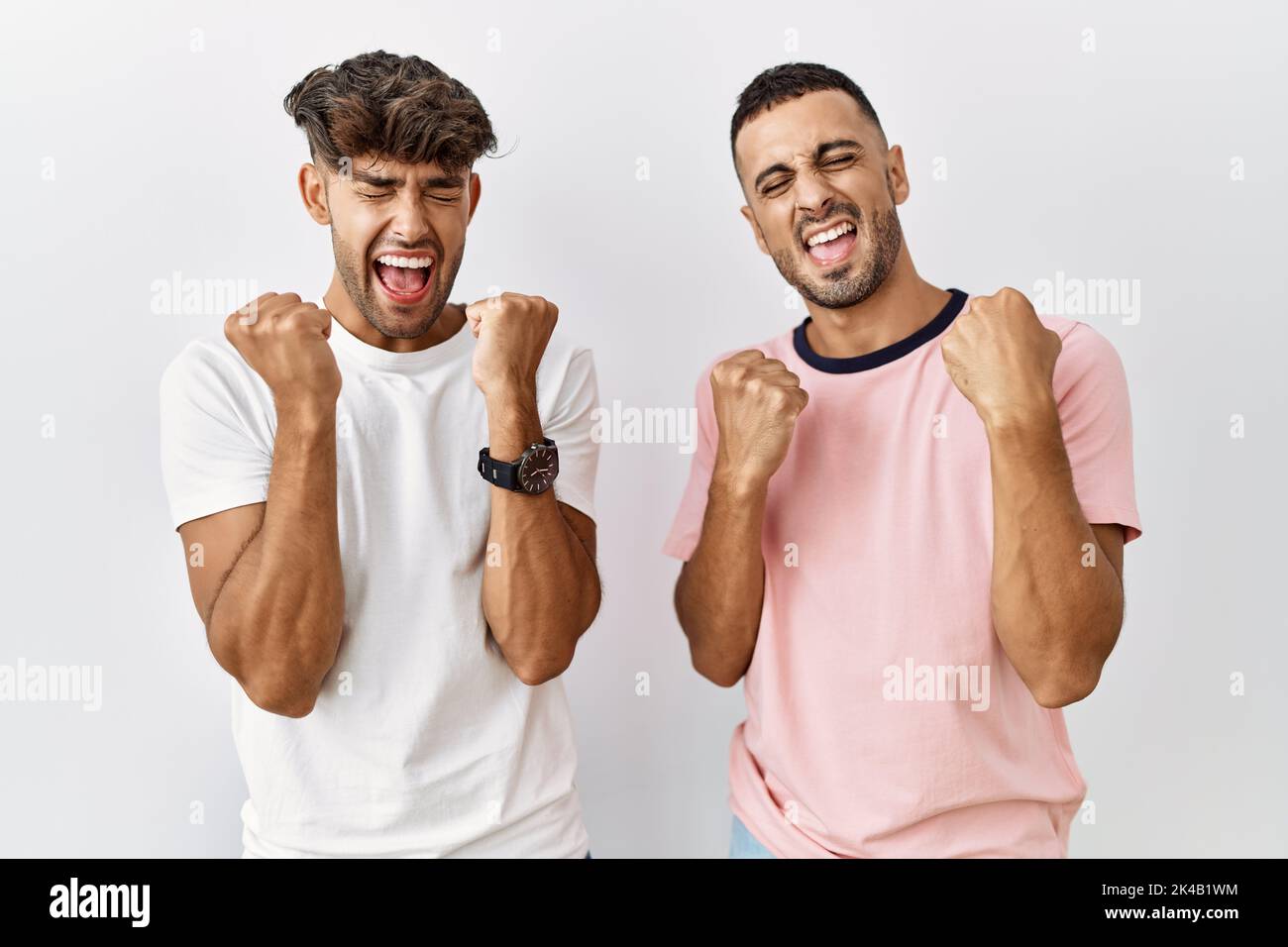 Young gay couple standing over isolated background excited for success ...