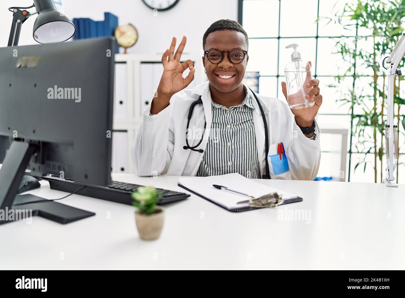 Young african doctor man holding hand sanitizer gel at the clinic doing ...