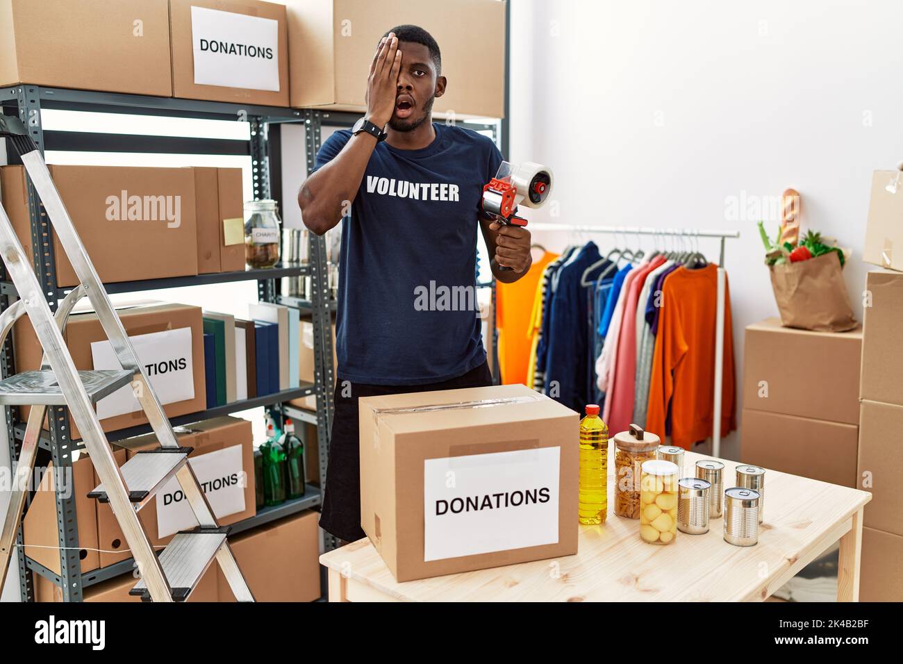 Young african american volunteer man packing donations box for charity ...